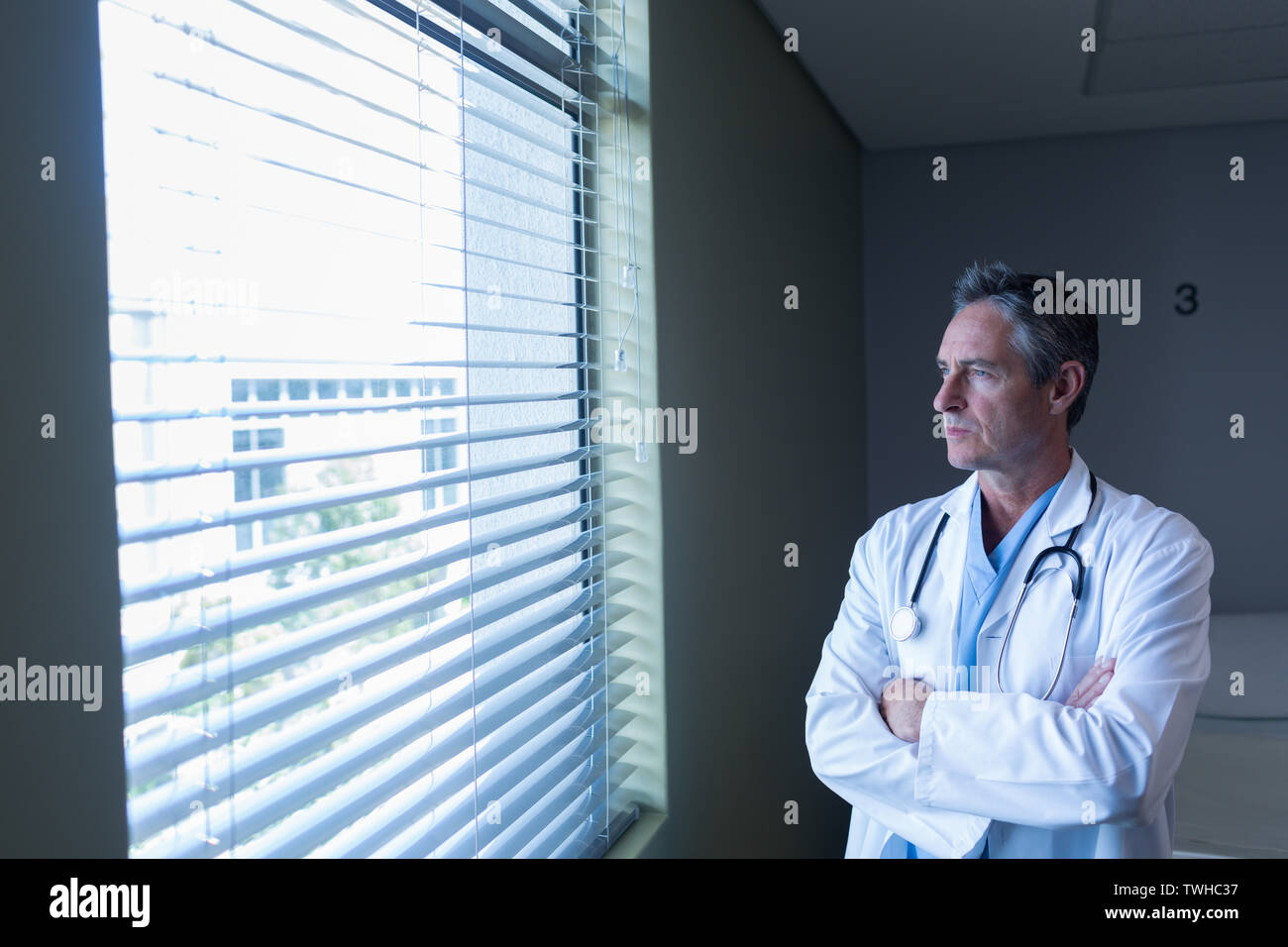 Mature male doctor looking through window in the hospital Stock Photo ...