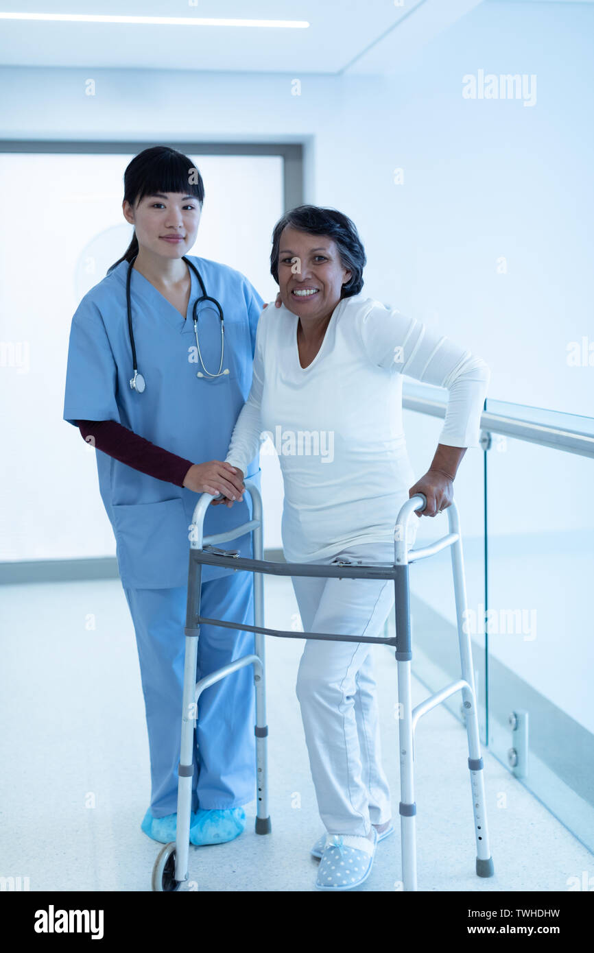 Female doctor helping female patient to walk with walker in the ...