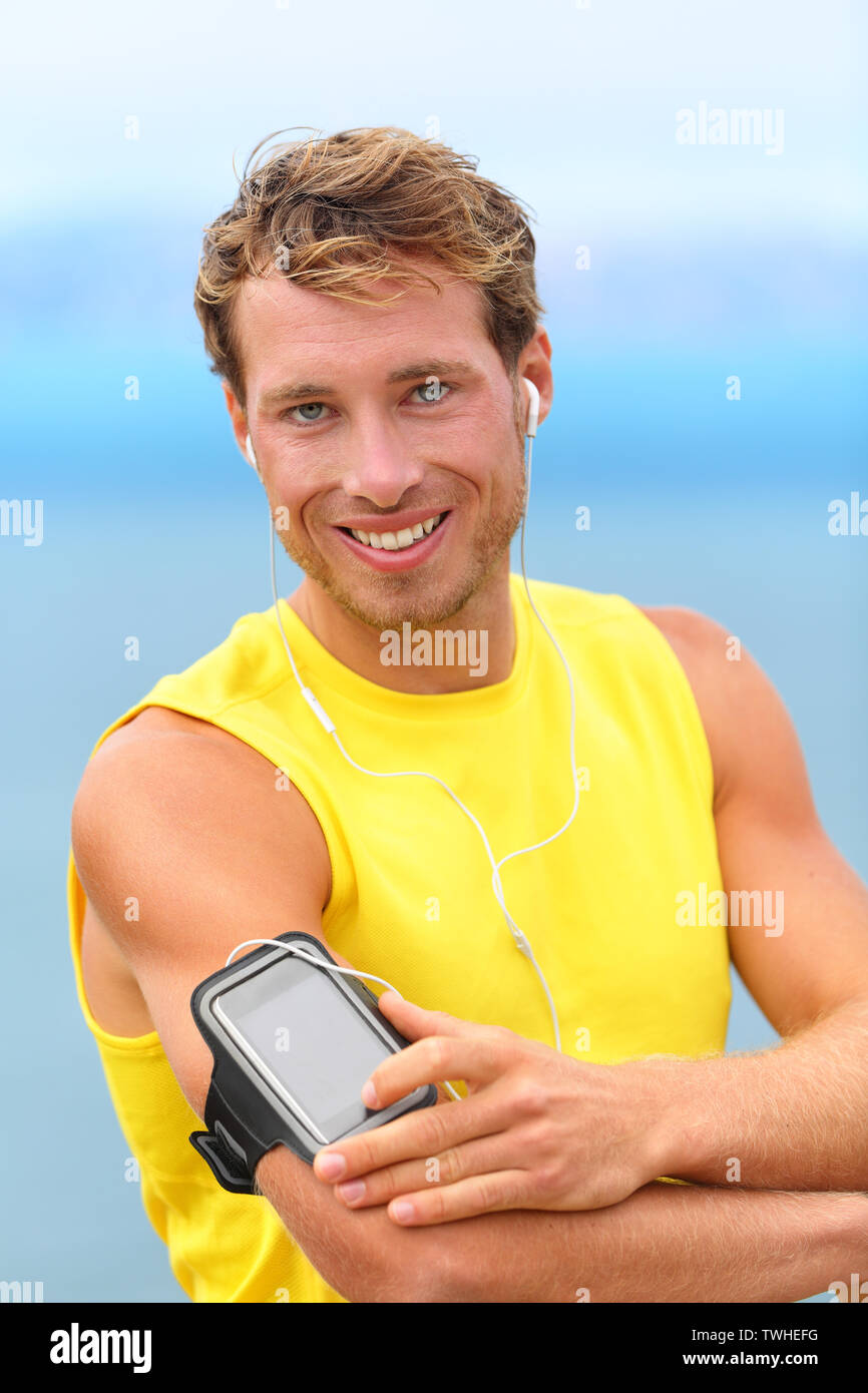 Running app on smartphone. Male runner listening to music adjusting ...