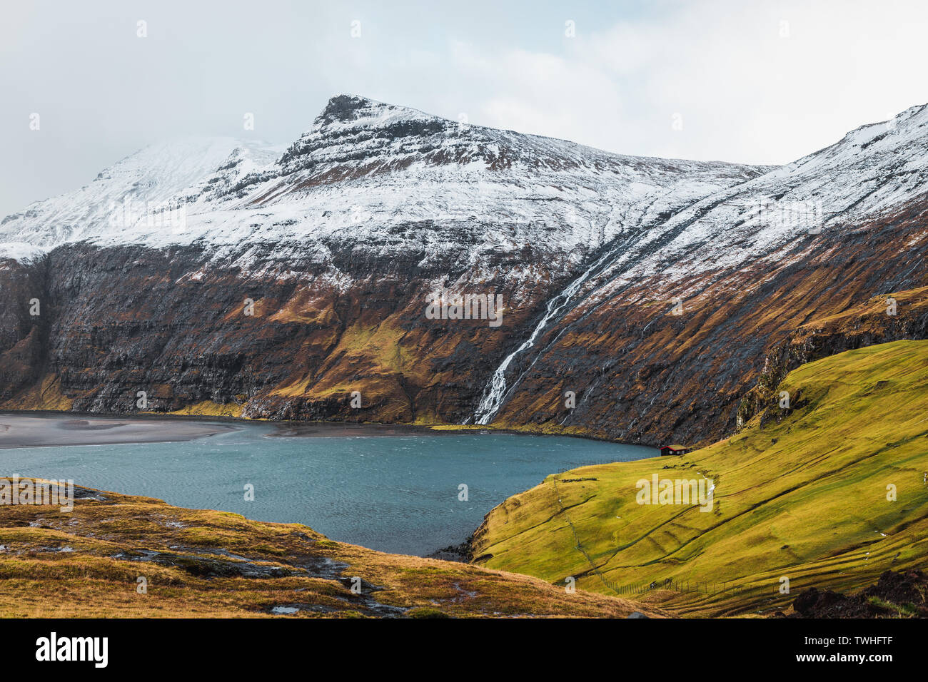 Lonely cabin in the fjord of Saksun during early spring with snow ...