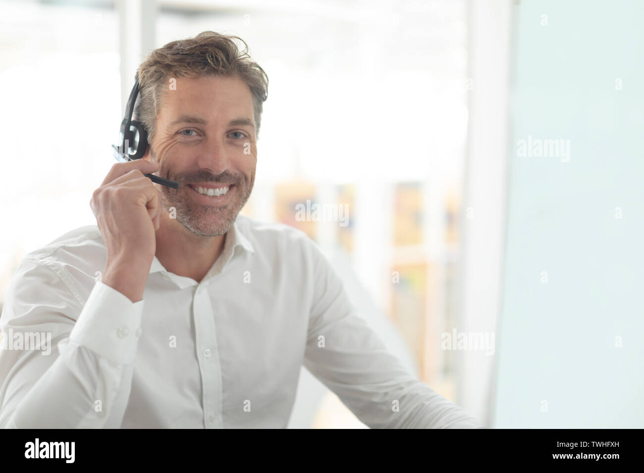 Customer service executive talking on headset at desk in a modern ...