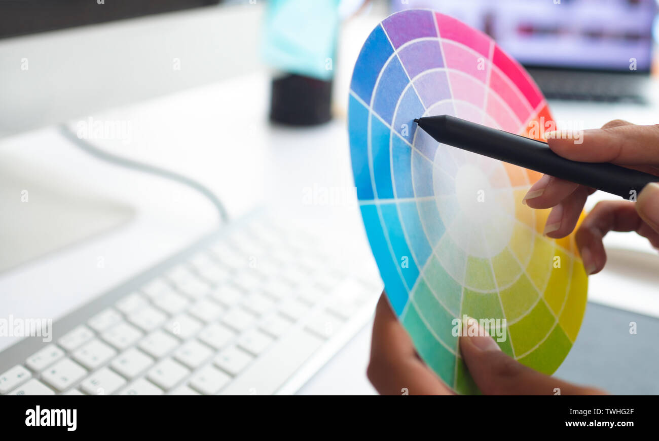 Female graphic designer working with color swatch at desk in a modern ...