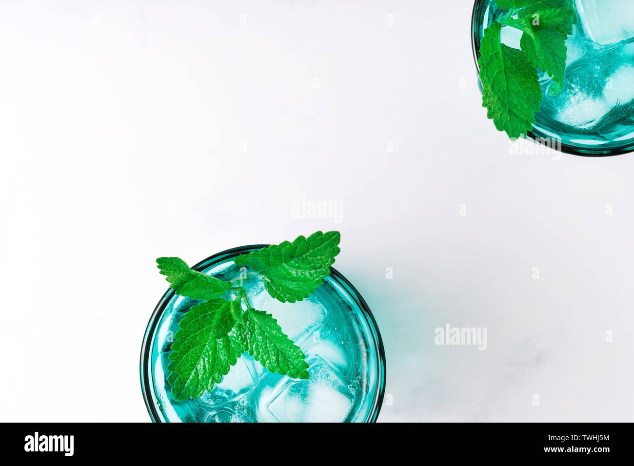 Two beautiful vintage turquoise glasses with cold drink and ice cubes ...