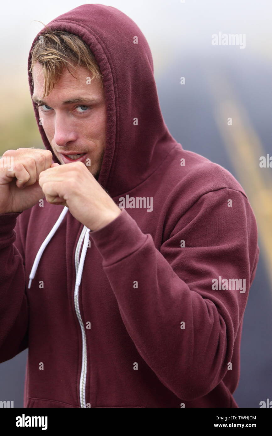 Fitness boxer boxing outside on road in hoodie. Man punching and ...