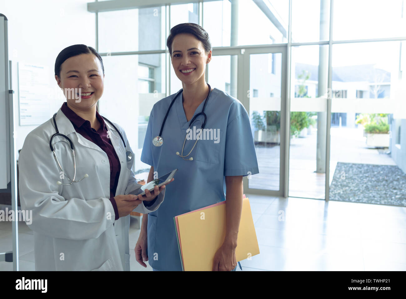 Female doctor and nurse looking at camera in the lobby at hospital ...