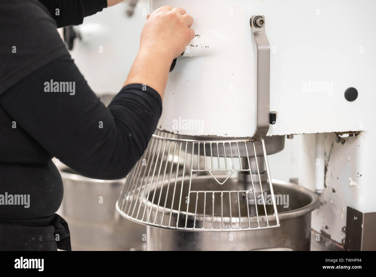 Confectionery factory worker standing and operating industrial dough ...