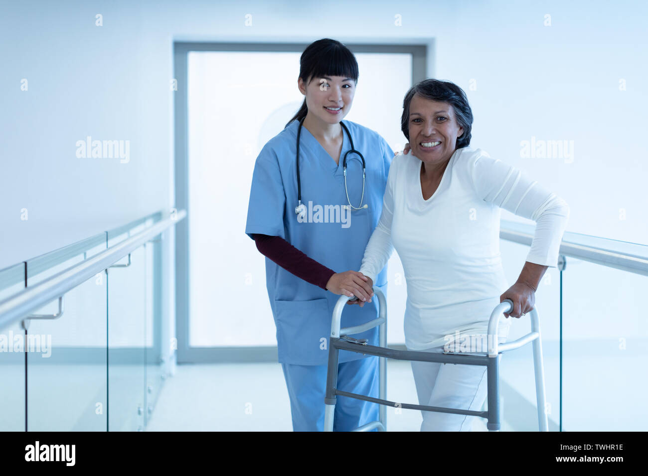Female doctor helping female patient to walk with walker in the ...