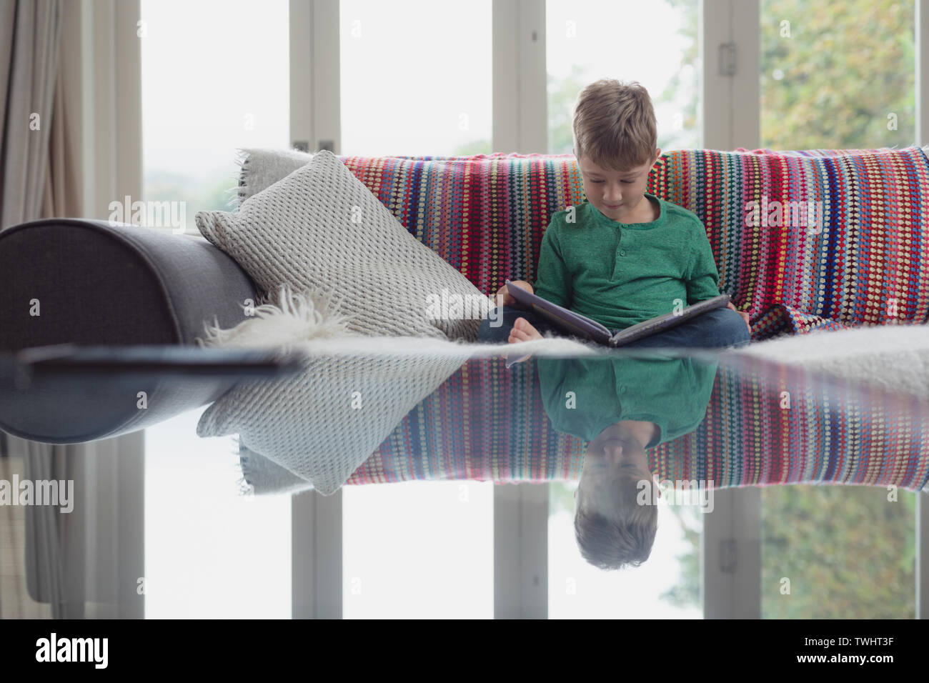 Cute boy reading a book on sofa in a comfortable home Stock Photo - Alamy