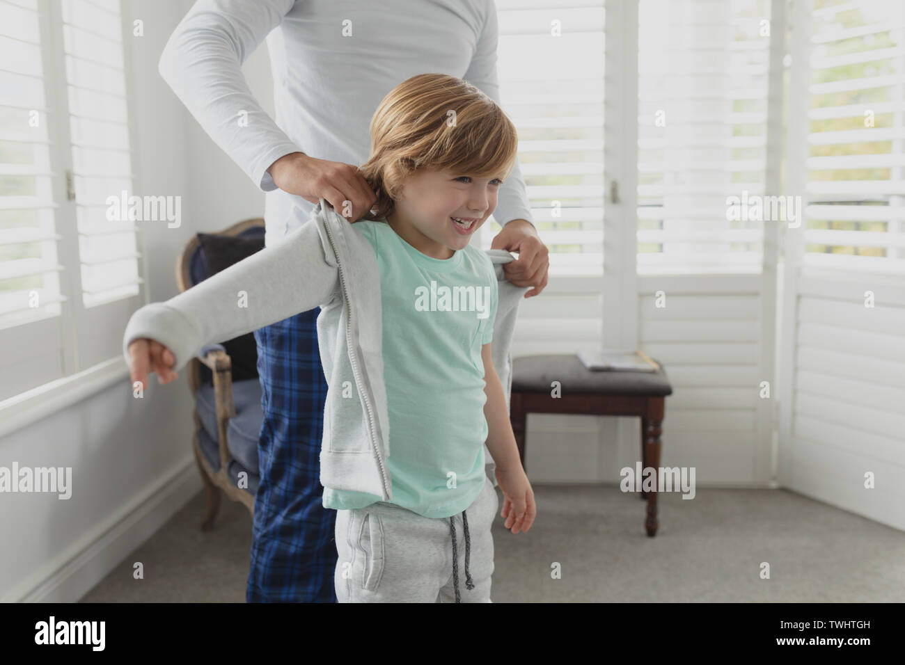 Father helping son putting on clothes Stock Photo - Alamy