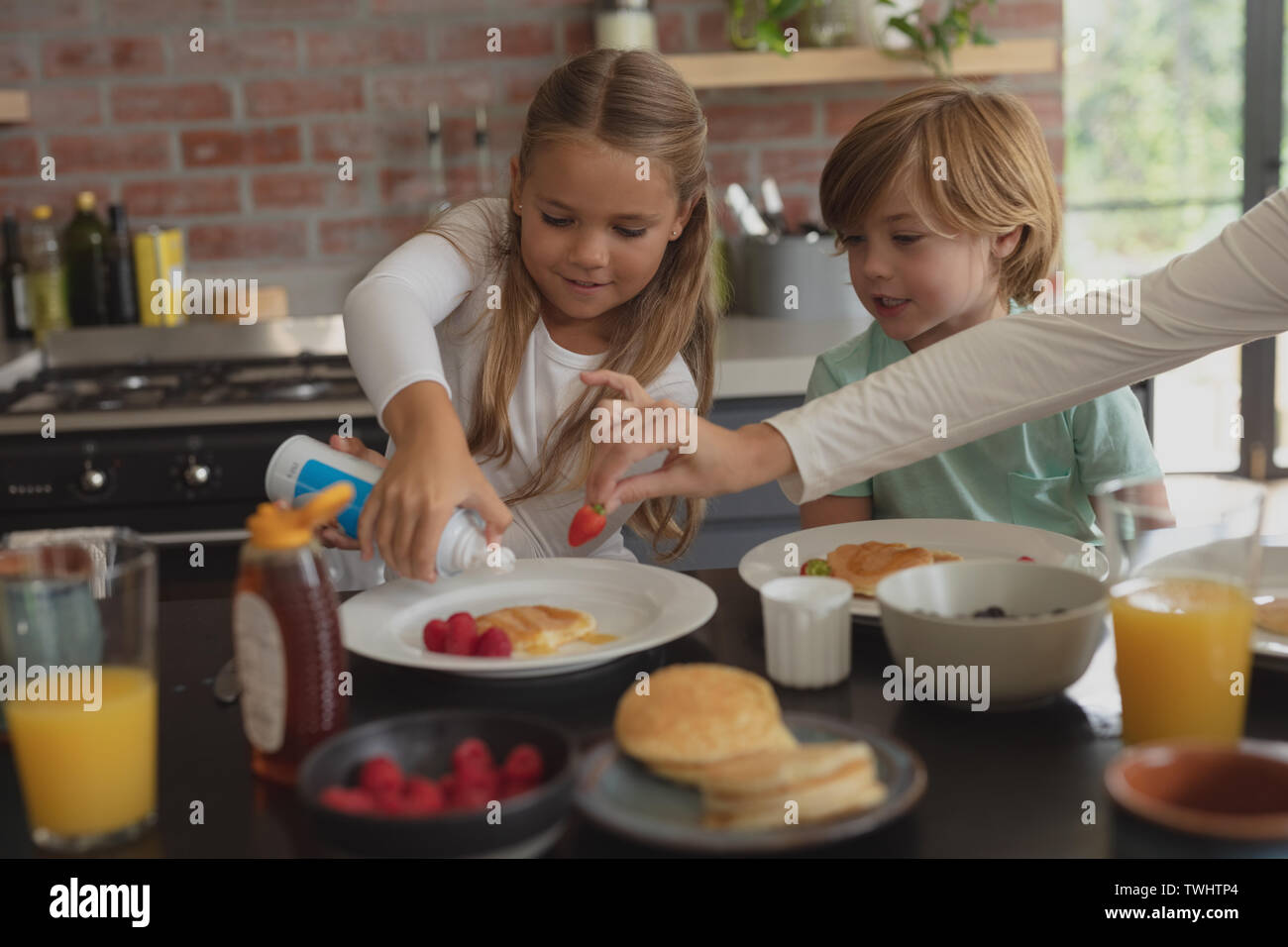 Caucasian siblings having food at dining table Stock Photo - Alamy