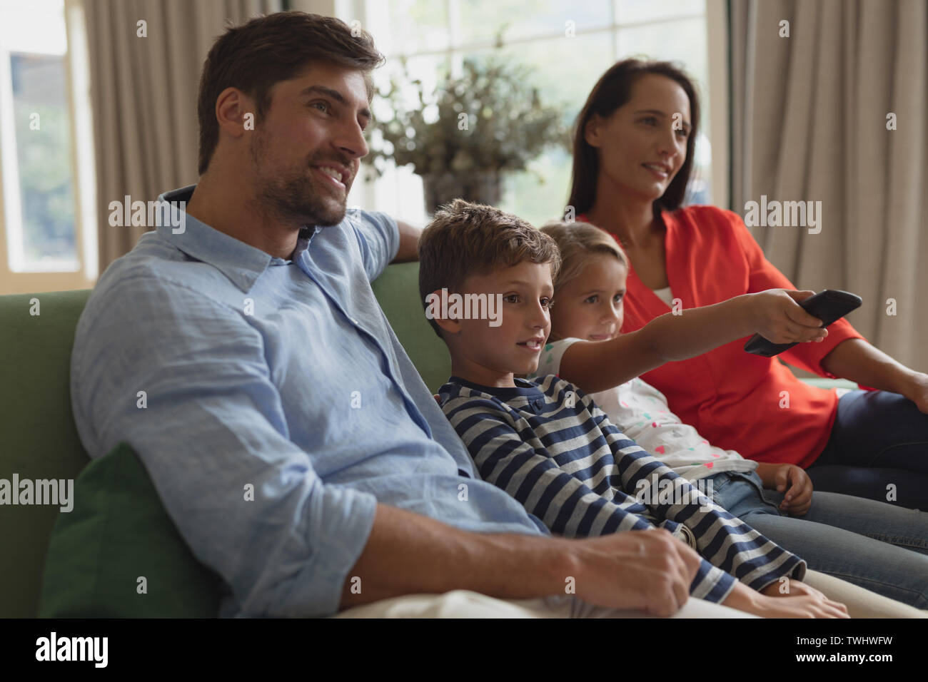 Family watching television in living room at home Stock Photo - Alamy