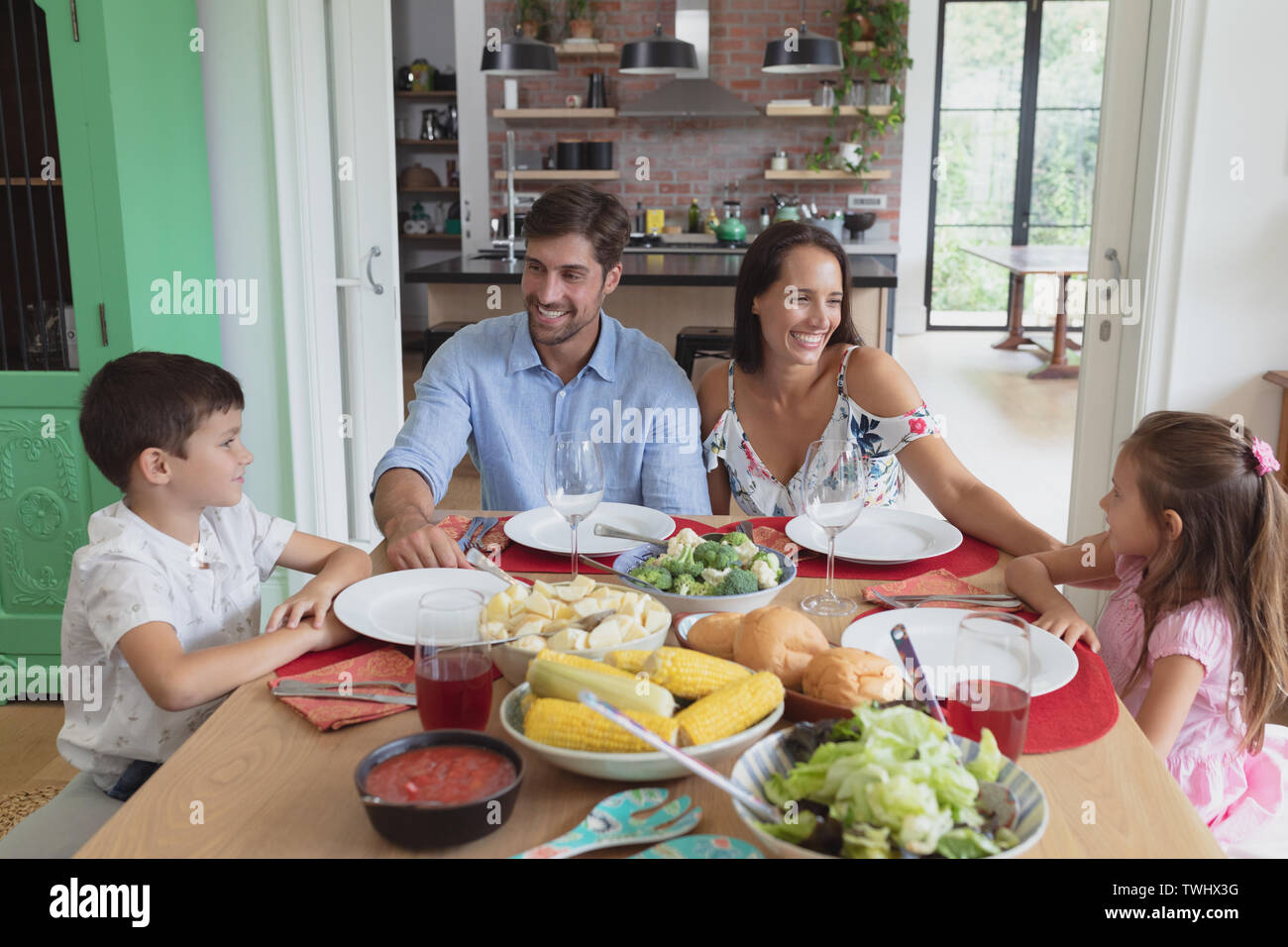 Family interacting with each other at dining table in comfortable home ...