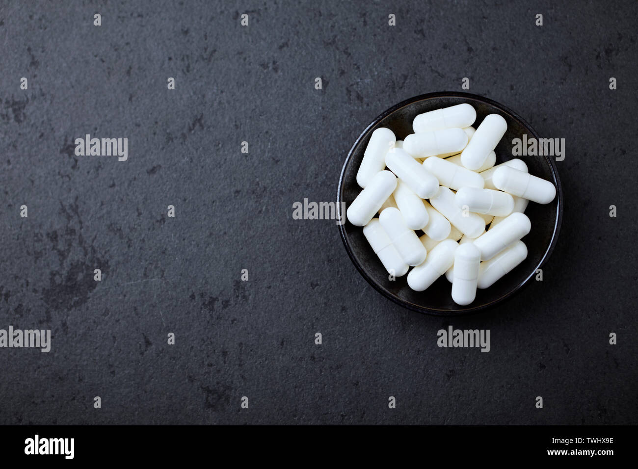 Creatine capsules. Bodybuilding food supplement on black stone ...