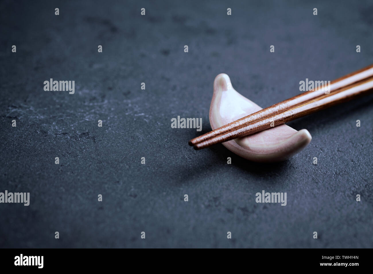 Wooden chopsticks and chopstick rest on black stone background. Close ...