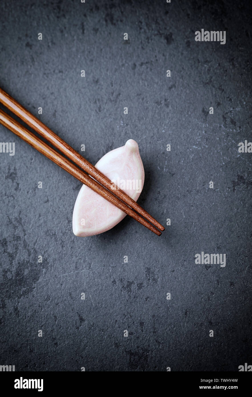 Wooden chopsticks and chopstick rest on dark stone background. Top view ...
