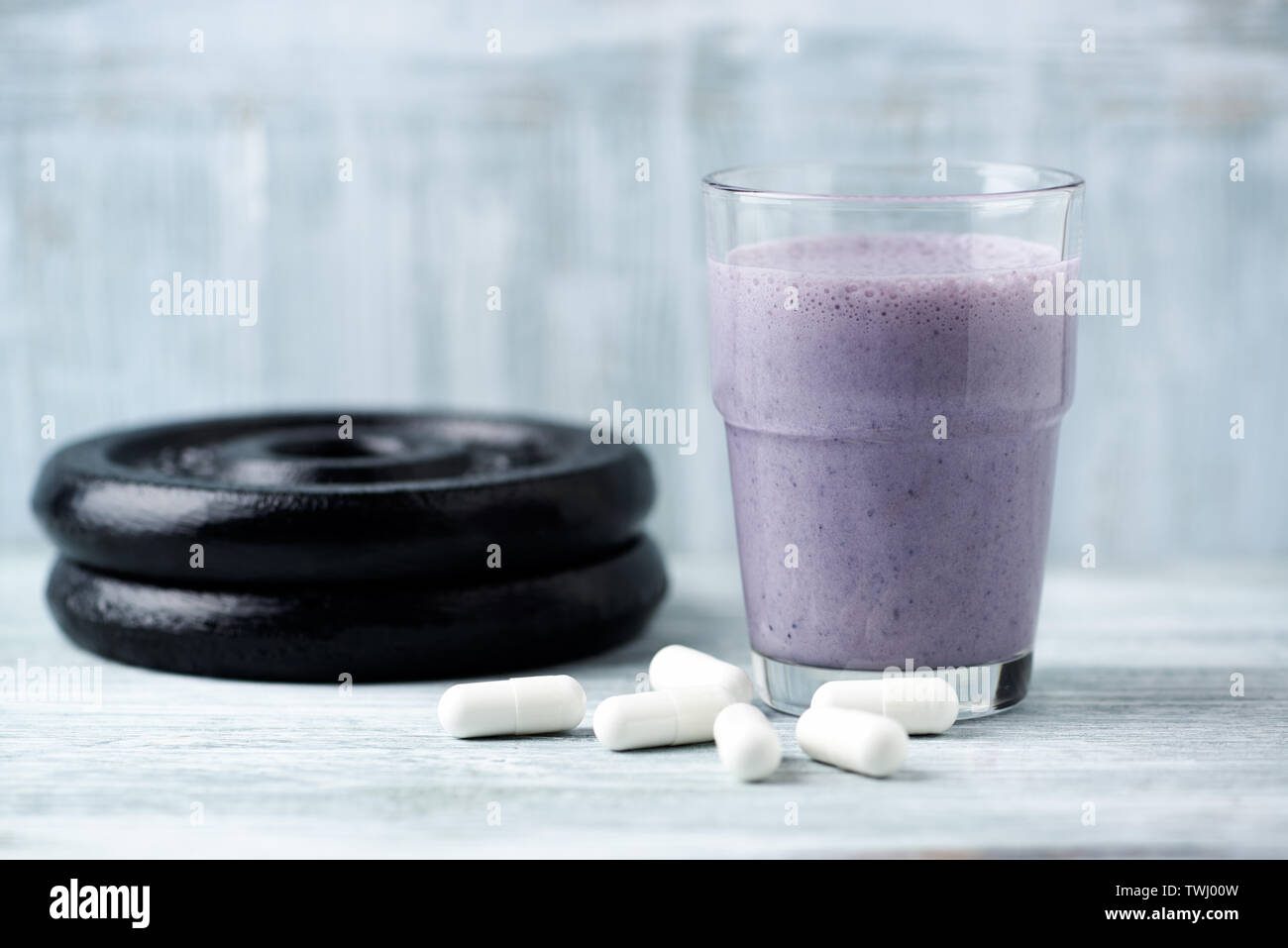 Glass of Protein Shake with milk and blueberries. Creatine capsules and ...