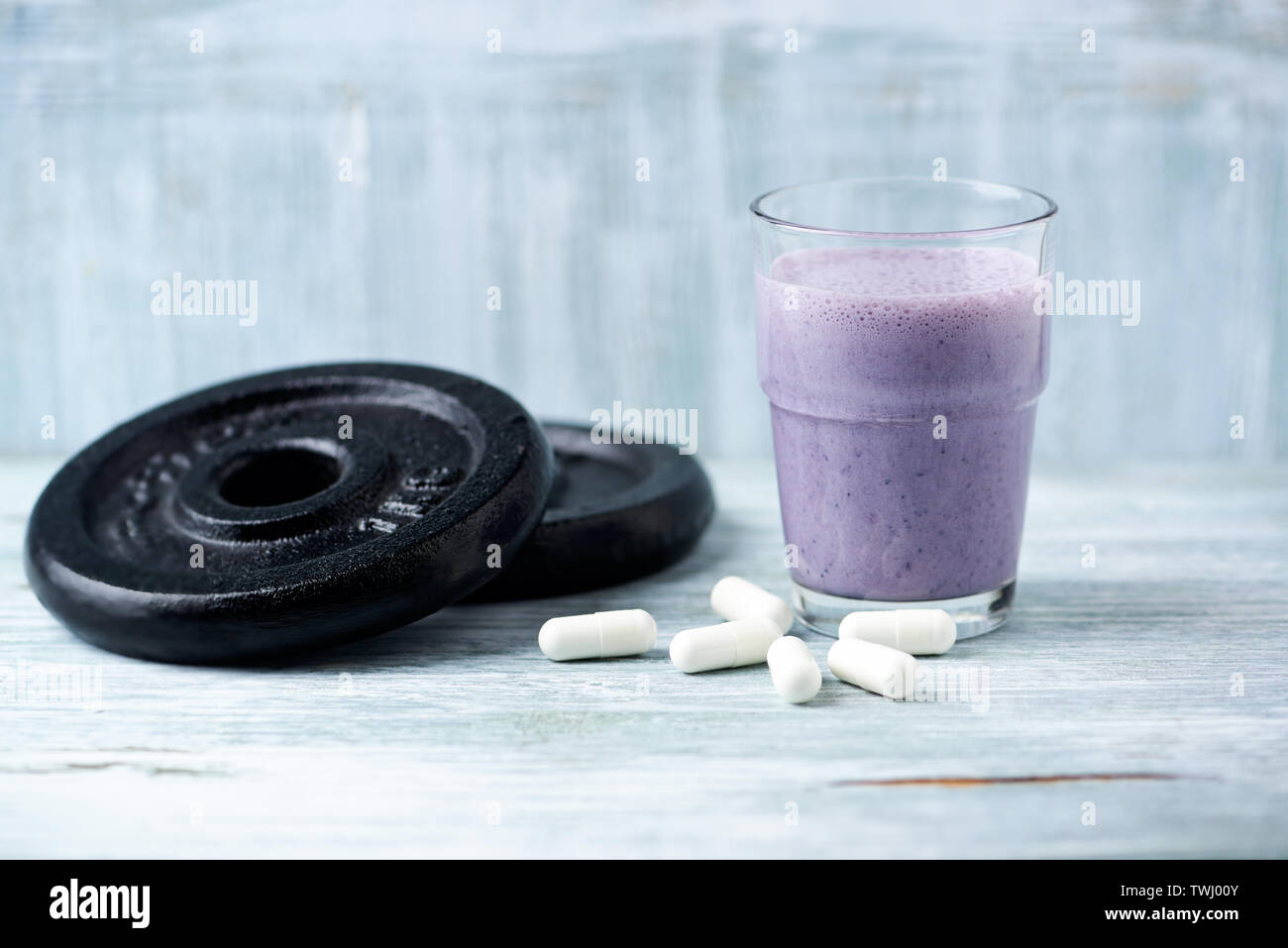 Glass of Protein Shake with milk and blueberries. Creatine capsules and ...