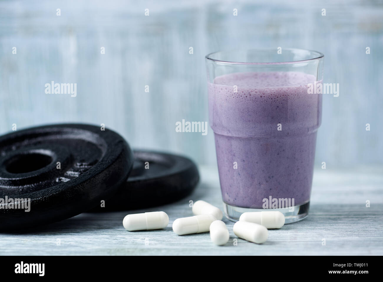 Glass of Protein Shake with milk and blueberries. Creatine capsules and ...