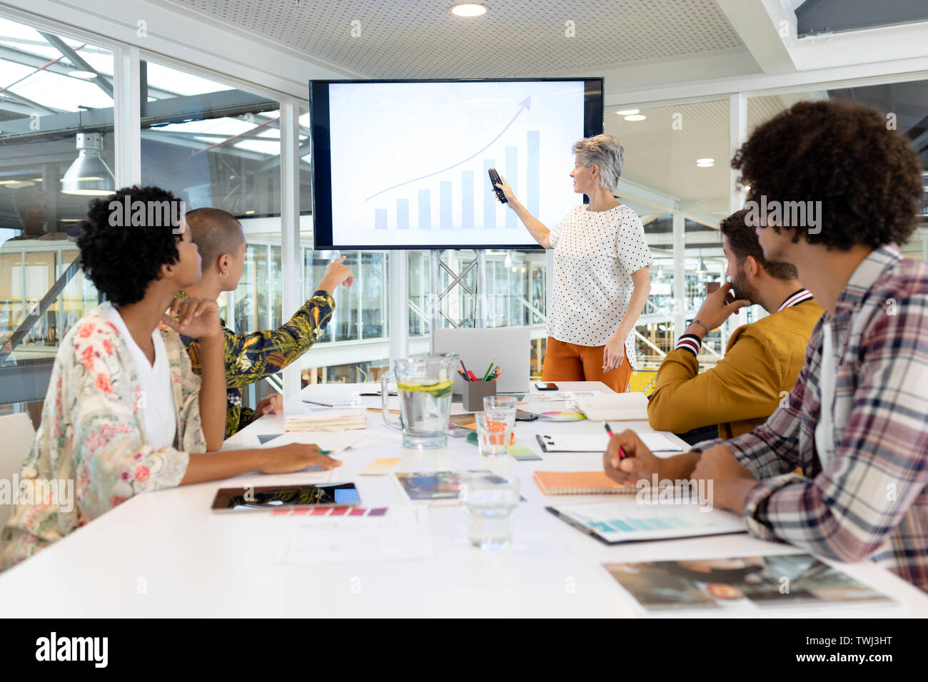 Businesswoman giving presentation on screen during meeting in a modern ...