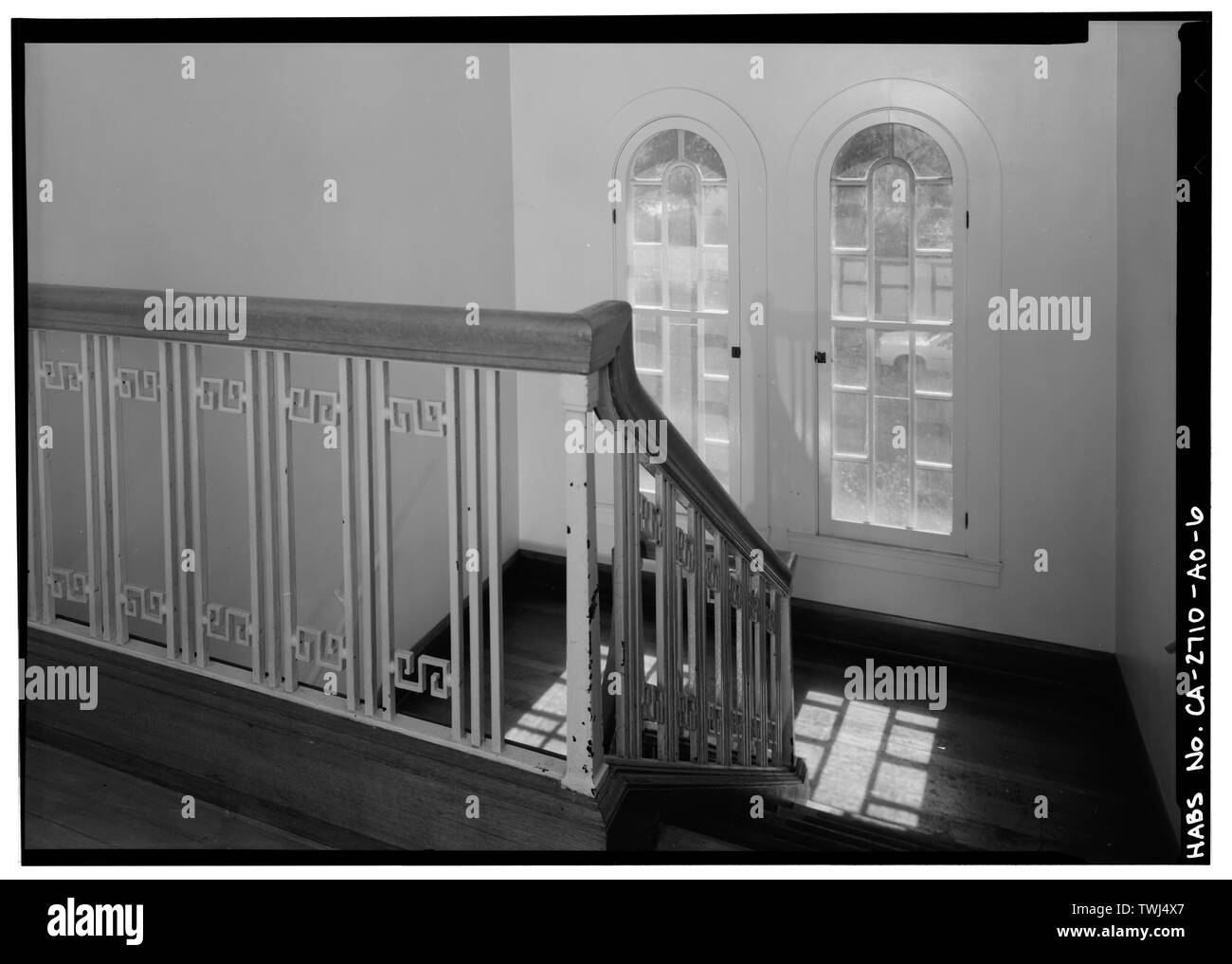 Second floor, wood staircase and two arched windows at landings ...