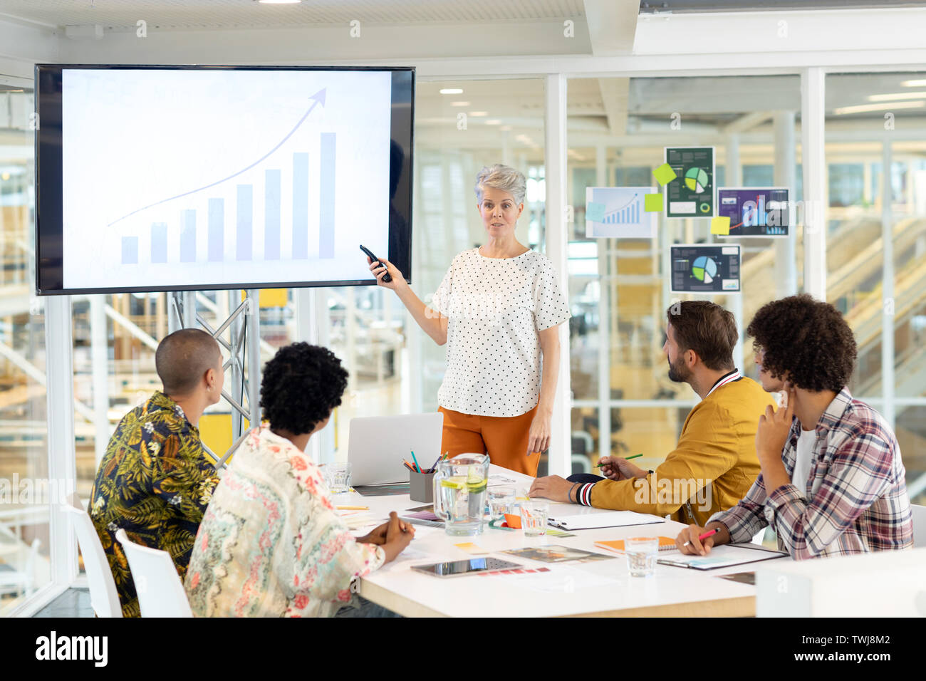 Businesswoman giving presentation on screen during meeting in a modern ...