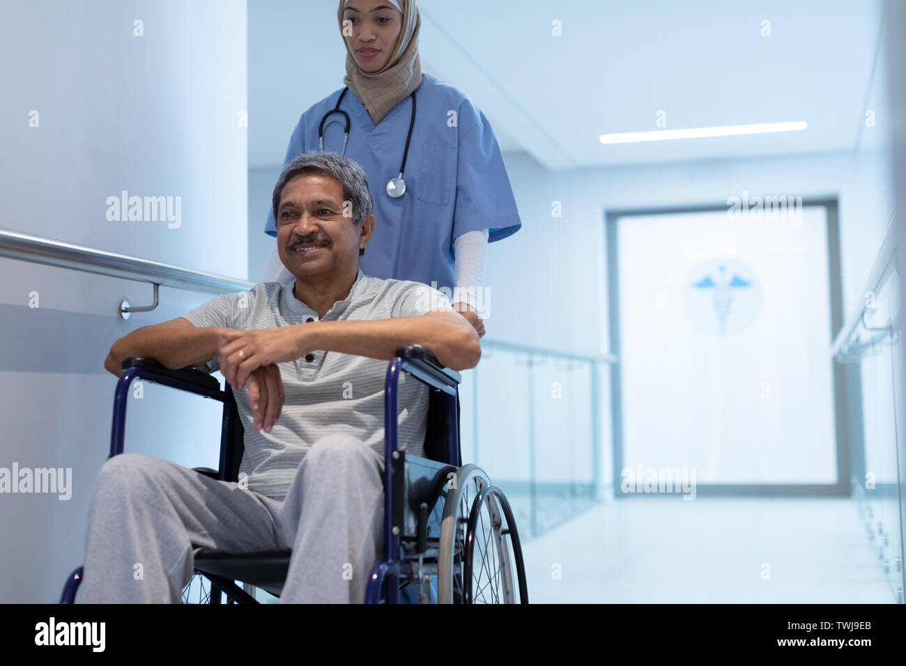 Female doctor pushing male patient in wheelchair at corridor Stock ...