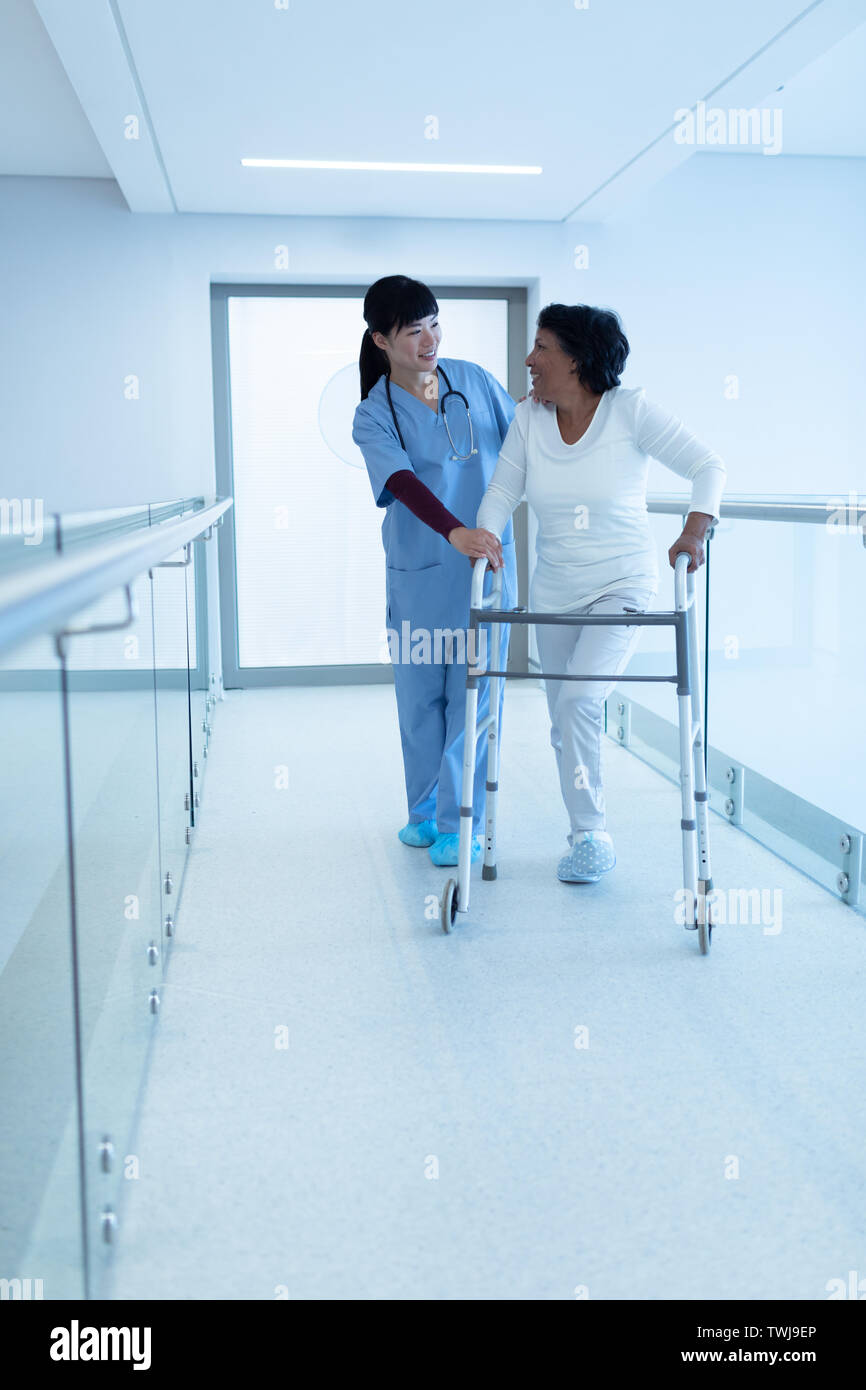 Female doctor helping female patient to walk with walker in the ...