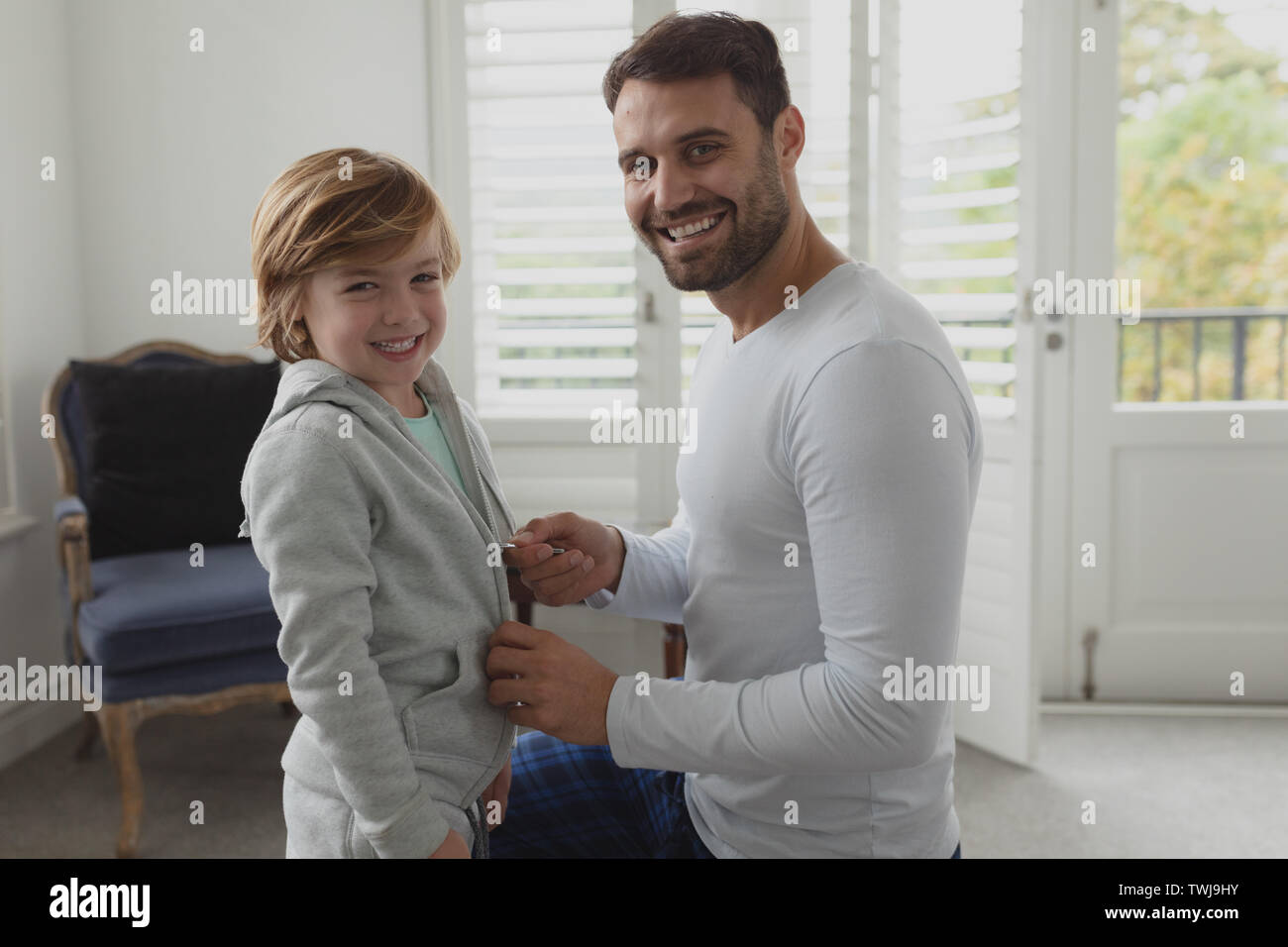 Father helping son putting on clothes Stock Photo - Alamy