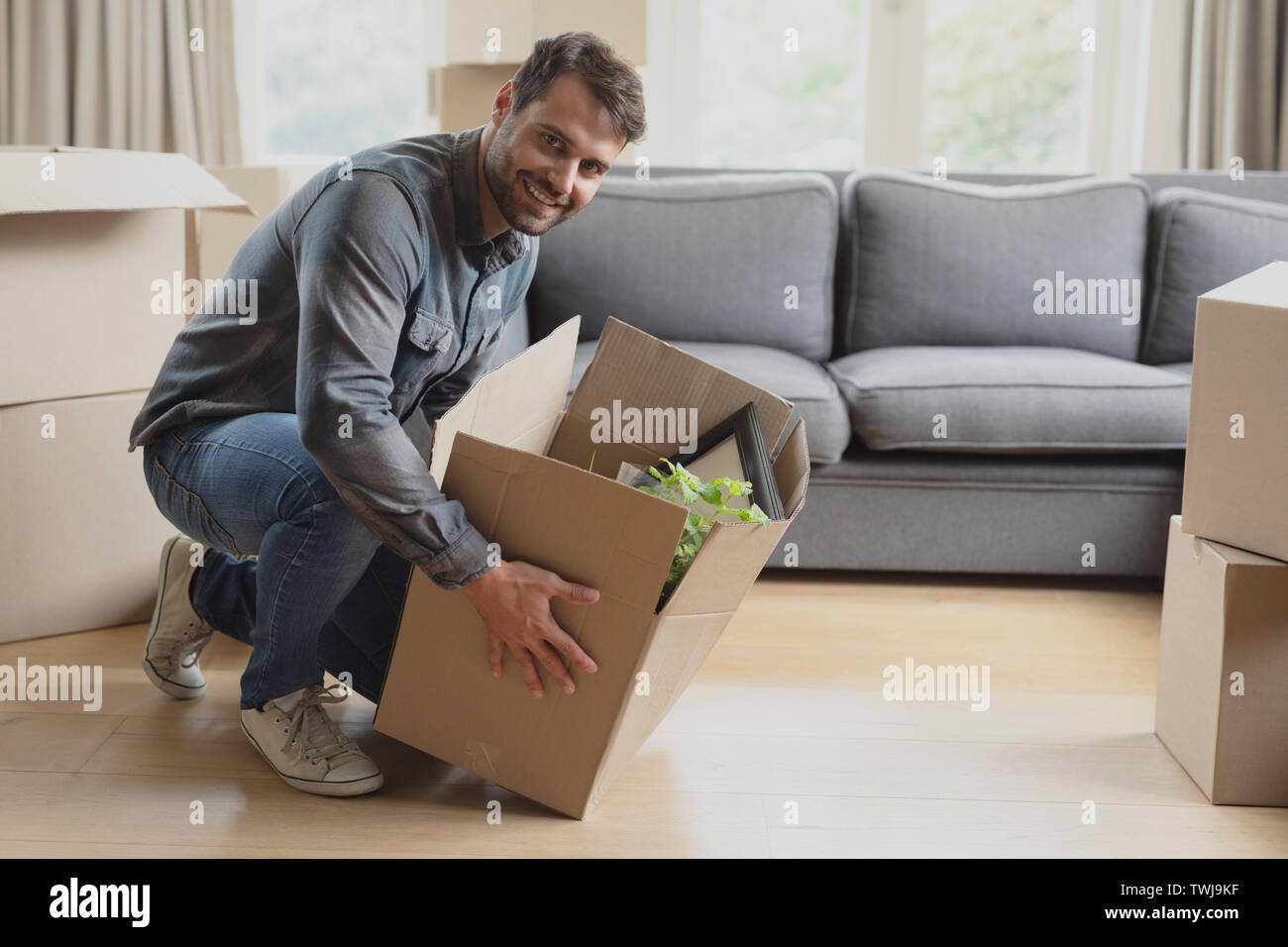 Man keeping down cardboard box in new home Stock Photo - Alamy