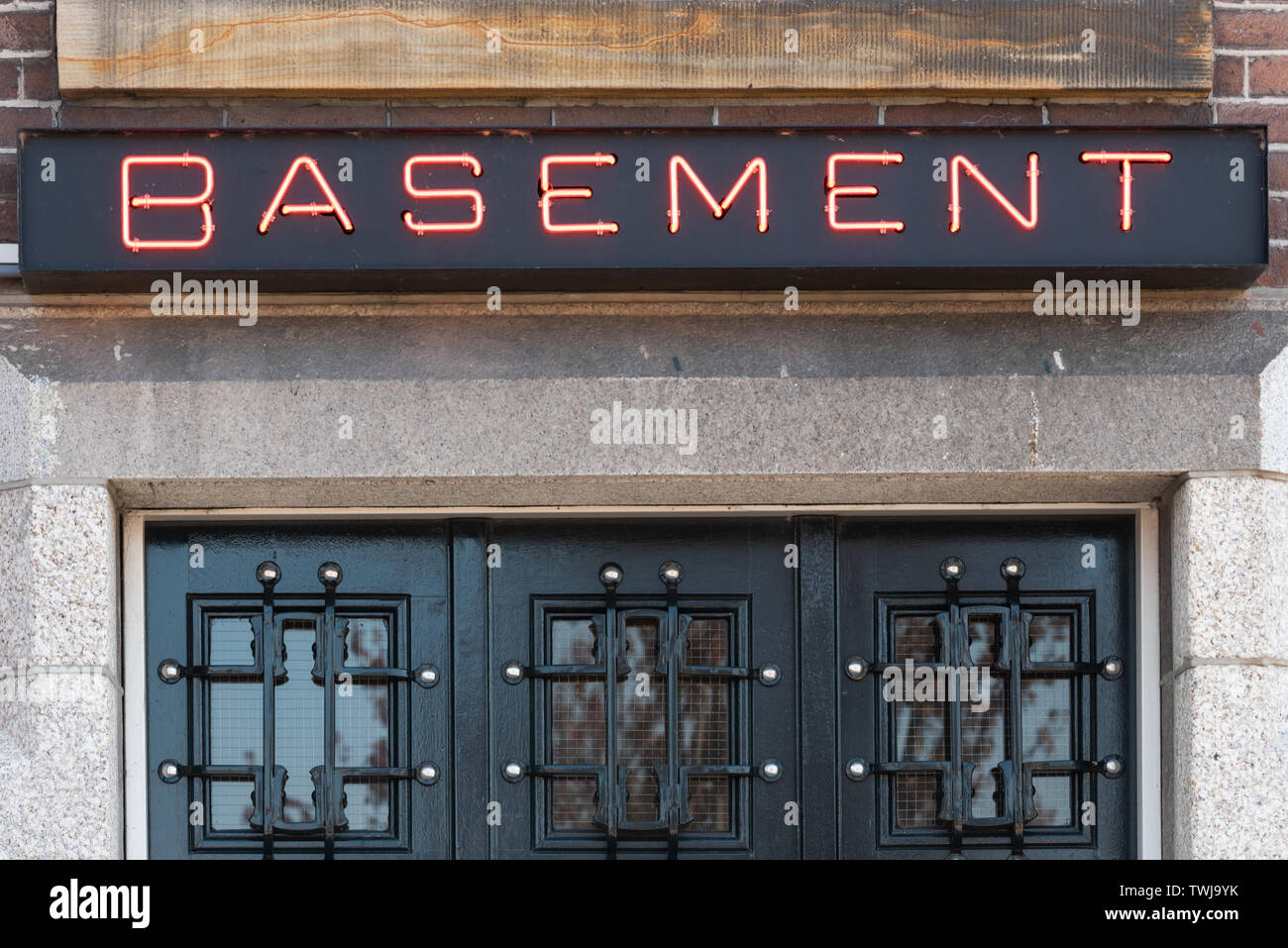 Basement red neon sign above a black door in daylight Stock Photo - Alamy