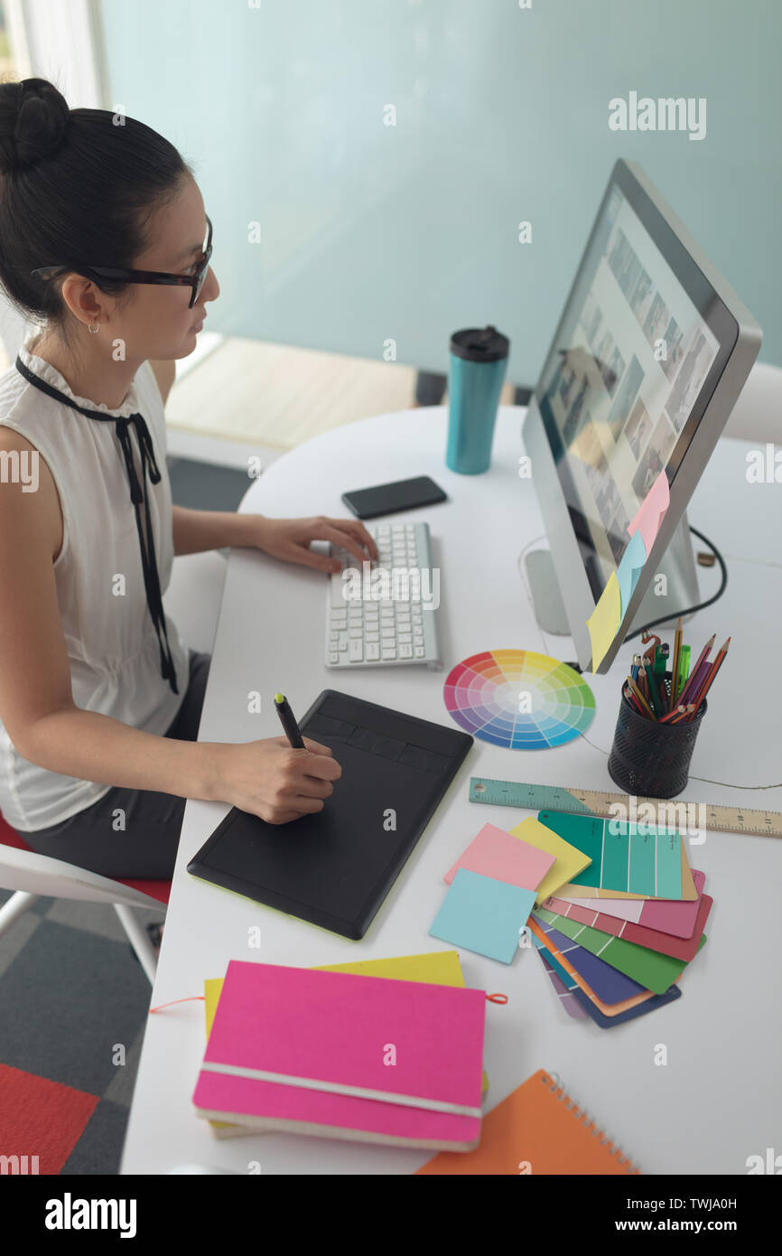 Female graphic designer using graphic tablet at desk in a modern office ...