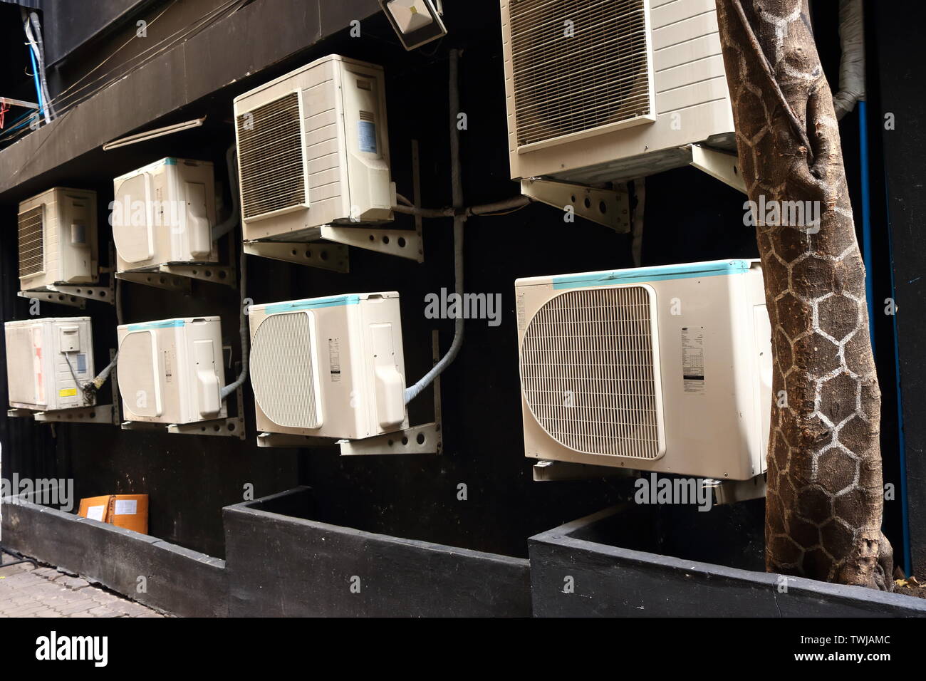 Group of condensing units of air conditioners fixed to the wall behind ...