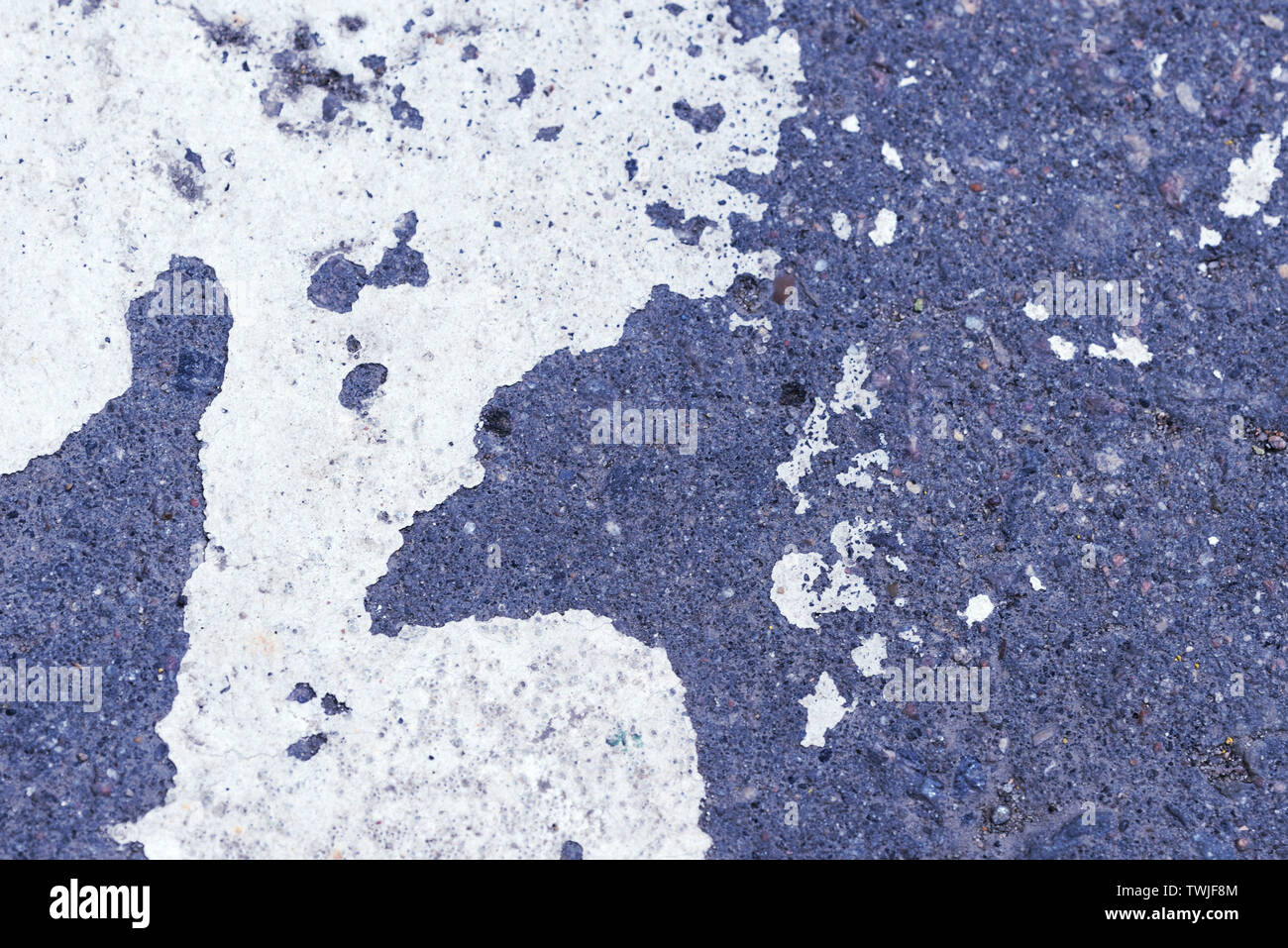White paint on the old asphalt surface close up. Blue color abstract ...