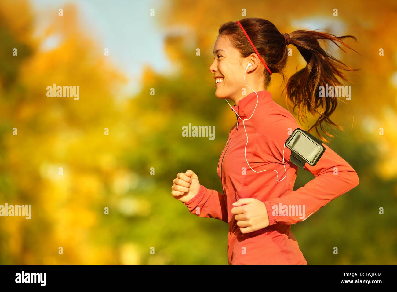 Woman runner running in fall autumn forest listening to music on ...
