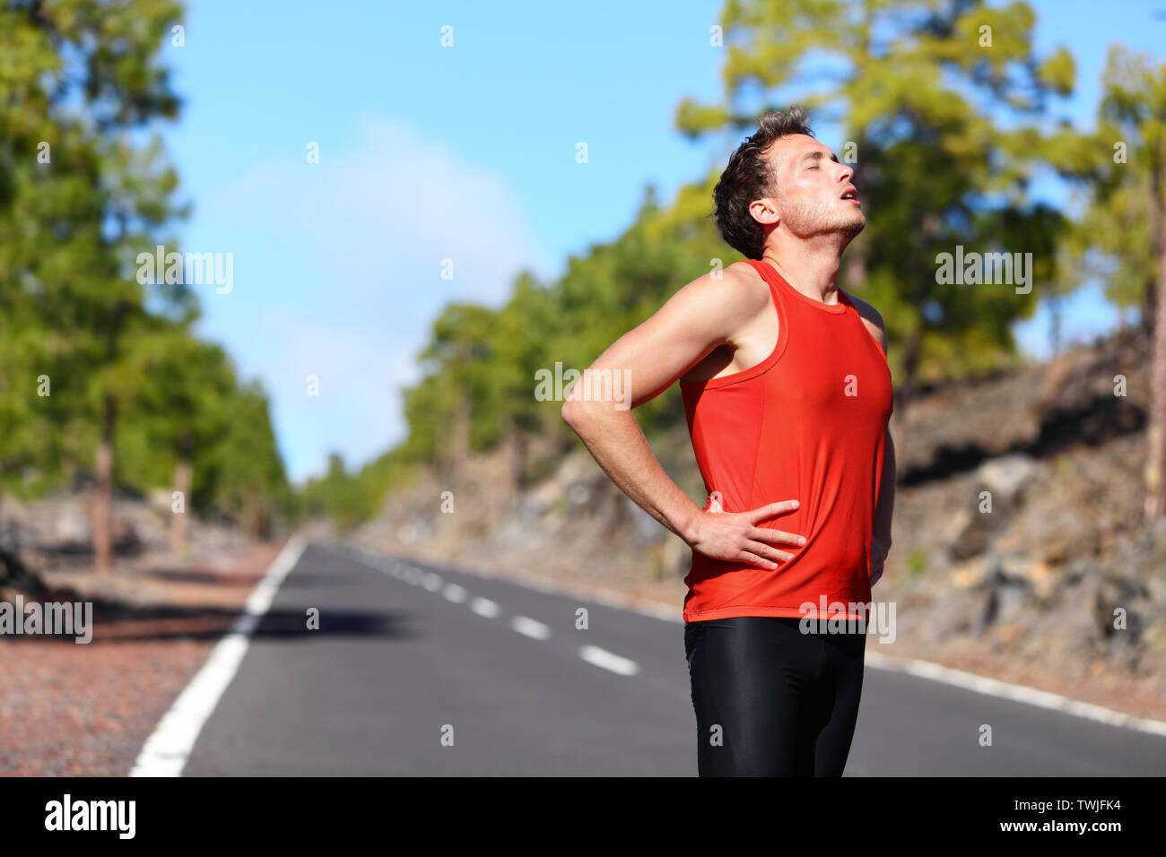 Runner resting tired and exhausted after running. Jogging man taking a ...