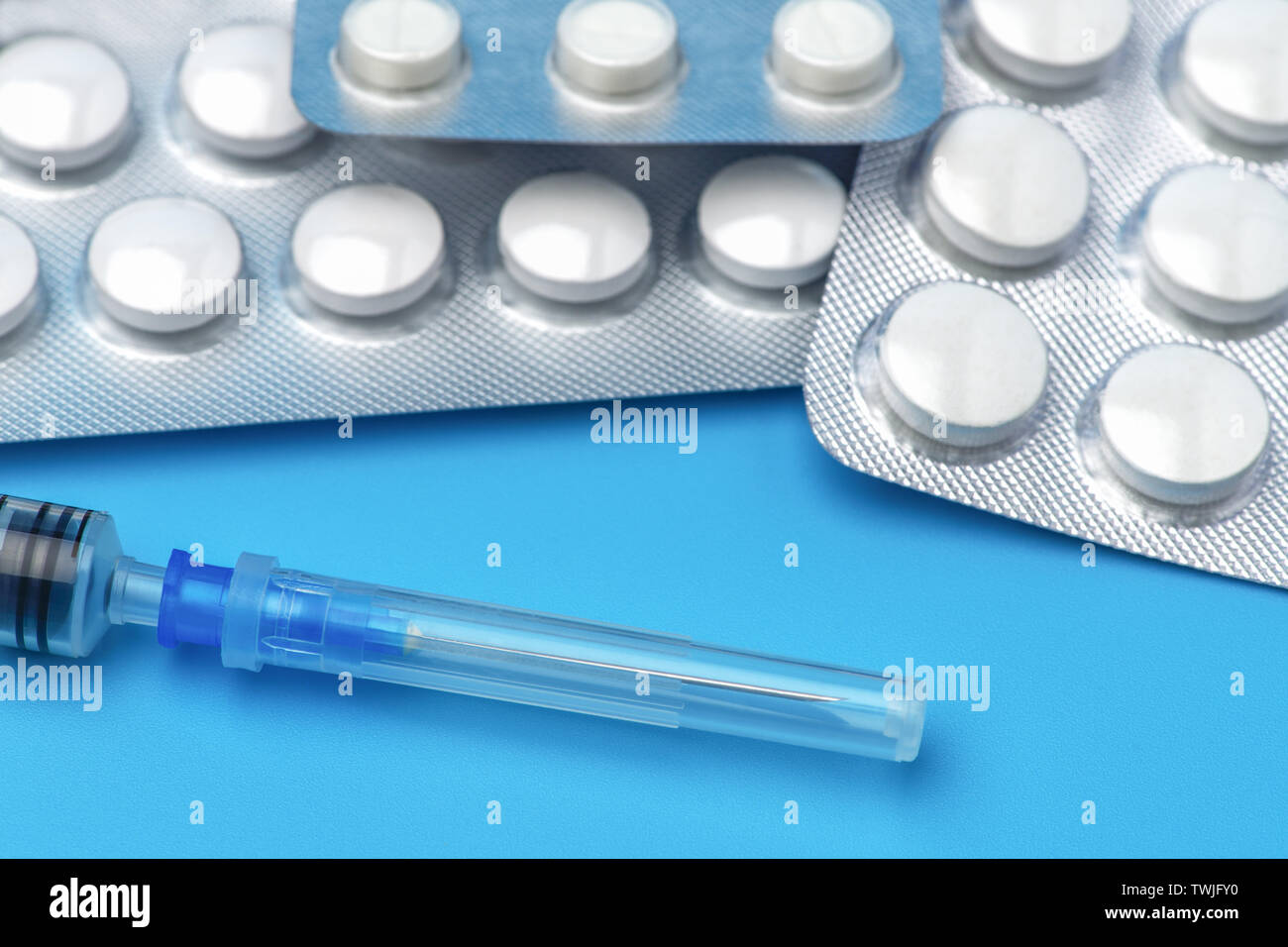 Many tablets are on a blue background, at the bottom is a syringe with ...