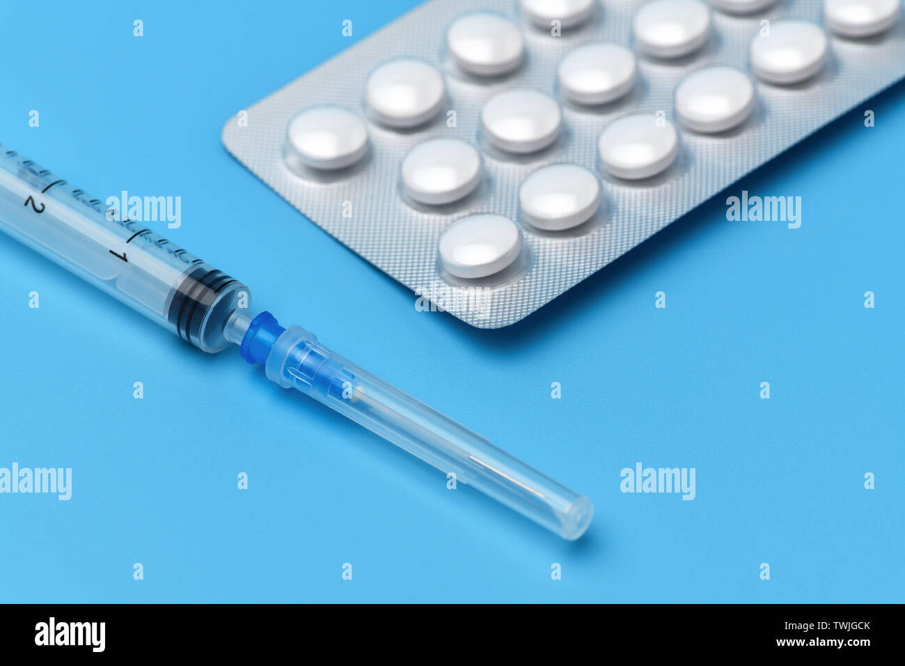 Many tablets are on a blue background, at the bottom is a syringe with ...