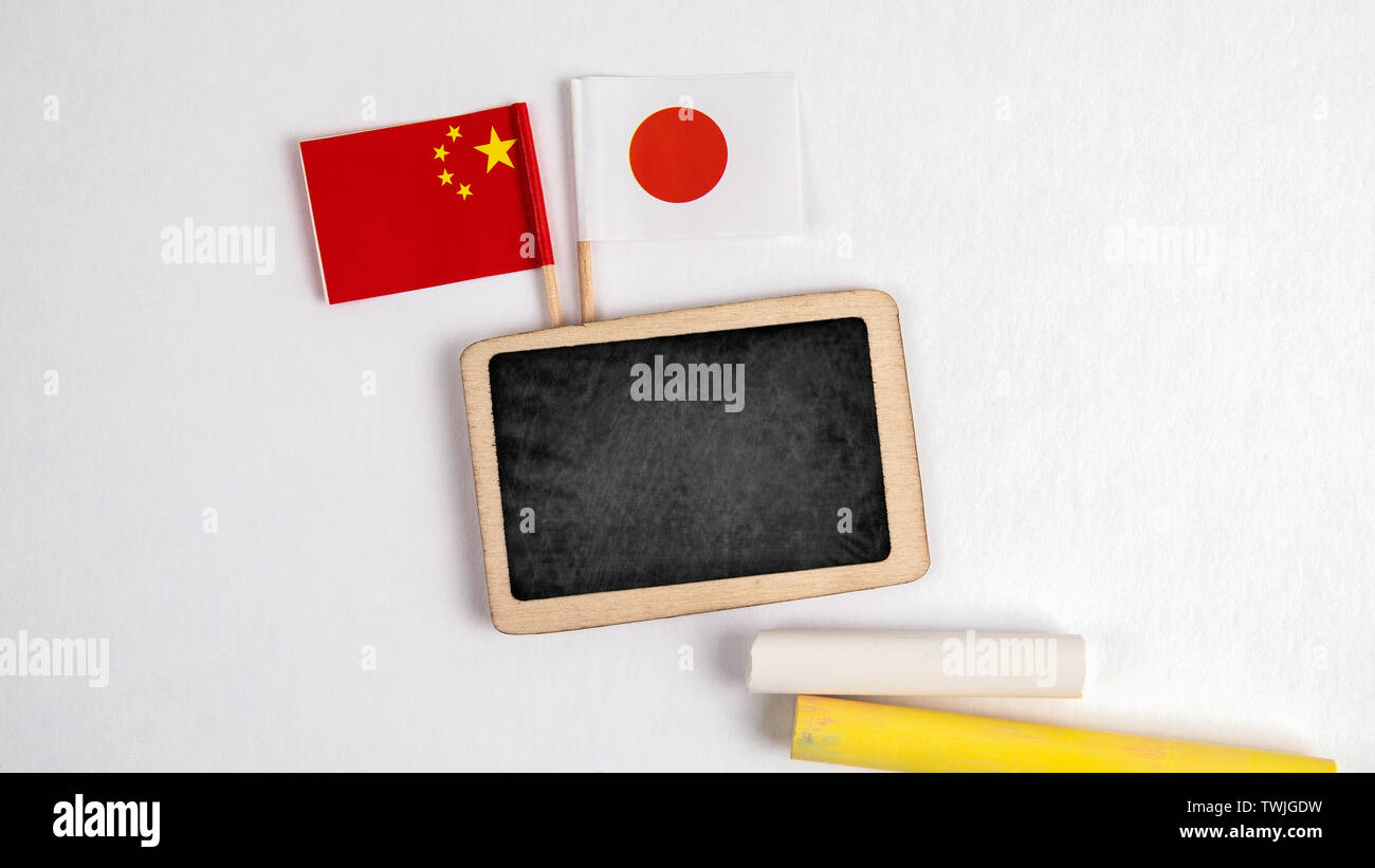 Japan and Chinese flags. Small whiteboard with chalk. Top view on a ...