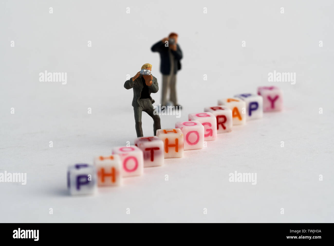 Miniature Photographers taking pictures behind a Group Of Letters ...