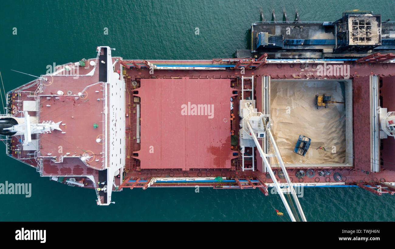Cranes working on cargo ship transporting sugar, Aerial pullback ...