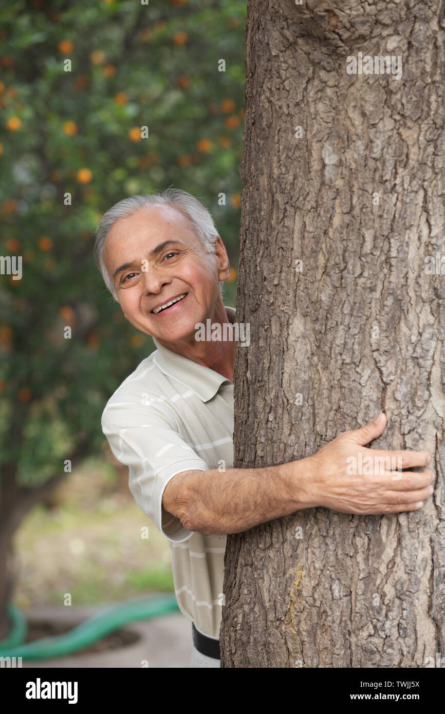 Portrait of an old man hugging a tree and smiling Stock Photo - Alamy