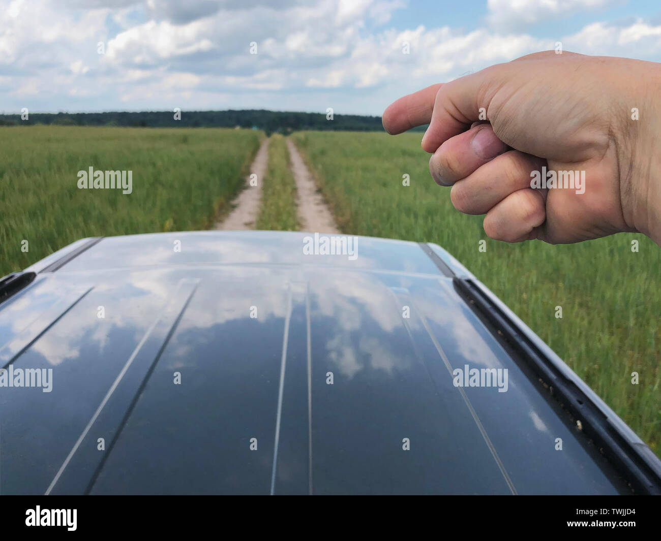 A hand pointing a way to go, the country road meets horizon in the ...