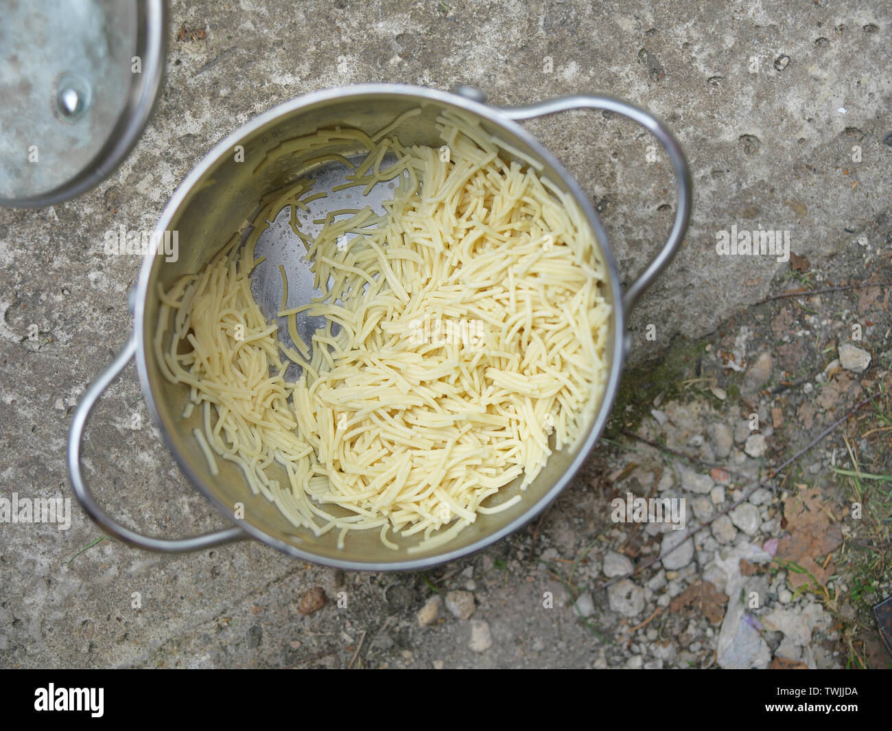 Half empty casserole with cooked noodles placed on the cement flkoor ...