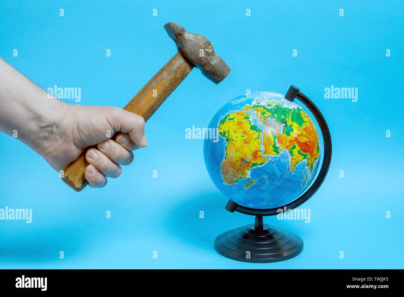 Male hand with an old rusty hammer, swings over the globe Stock Photo ...