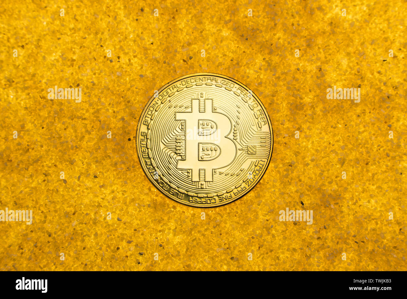 one bitcoin crypto coin on a shiny golden sand background with ...