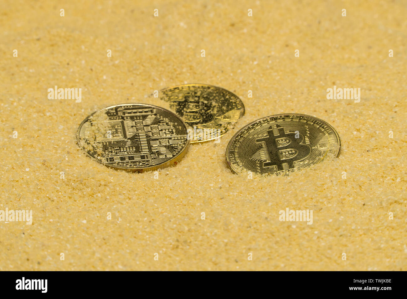 several bitcoin crypto coins on brilliant golden sand. finding and ...
