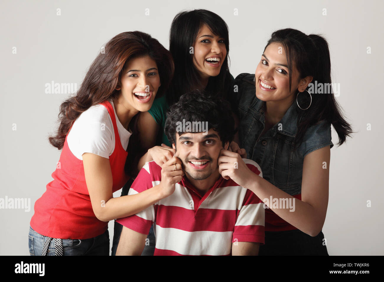 Three women pinching cheeks of a man and smiling Stock Photo - Alamy