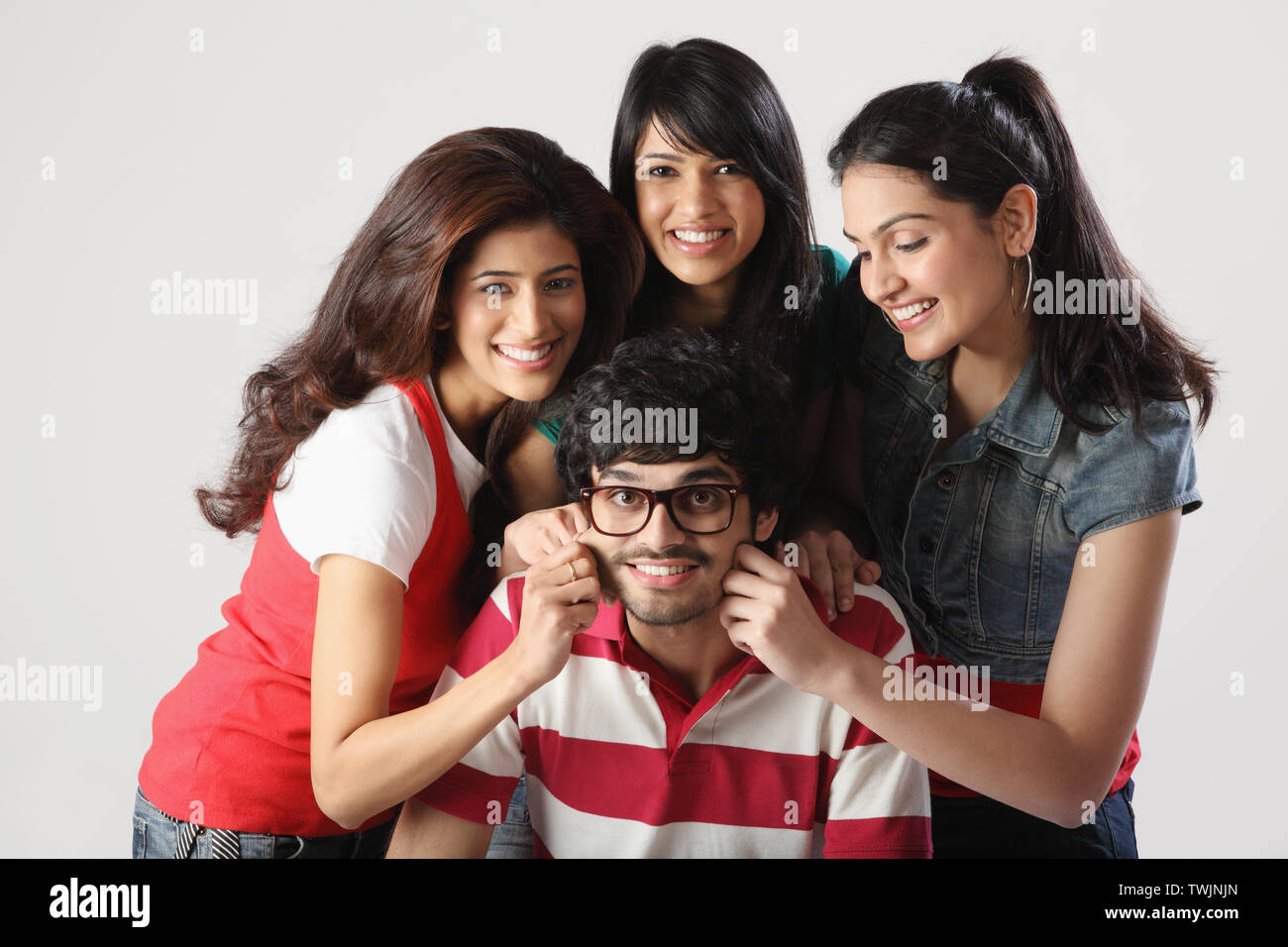 Three women pinching cheeks of a man and smiling Stock Photo - Alamy