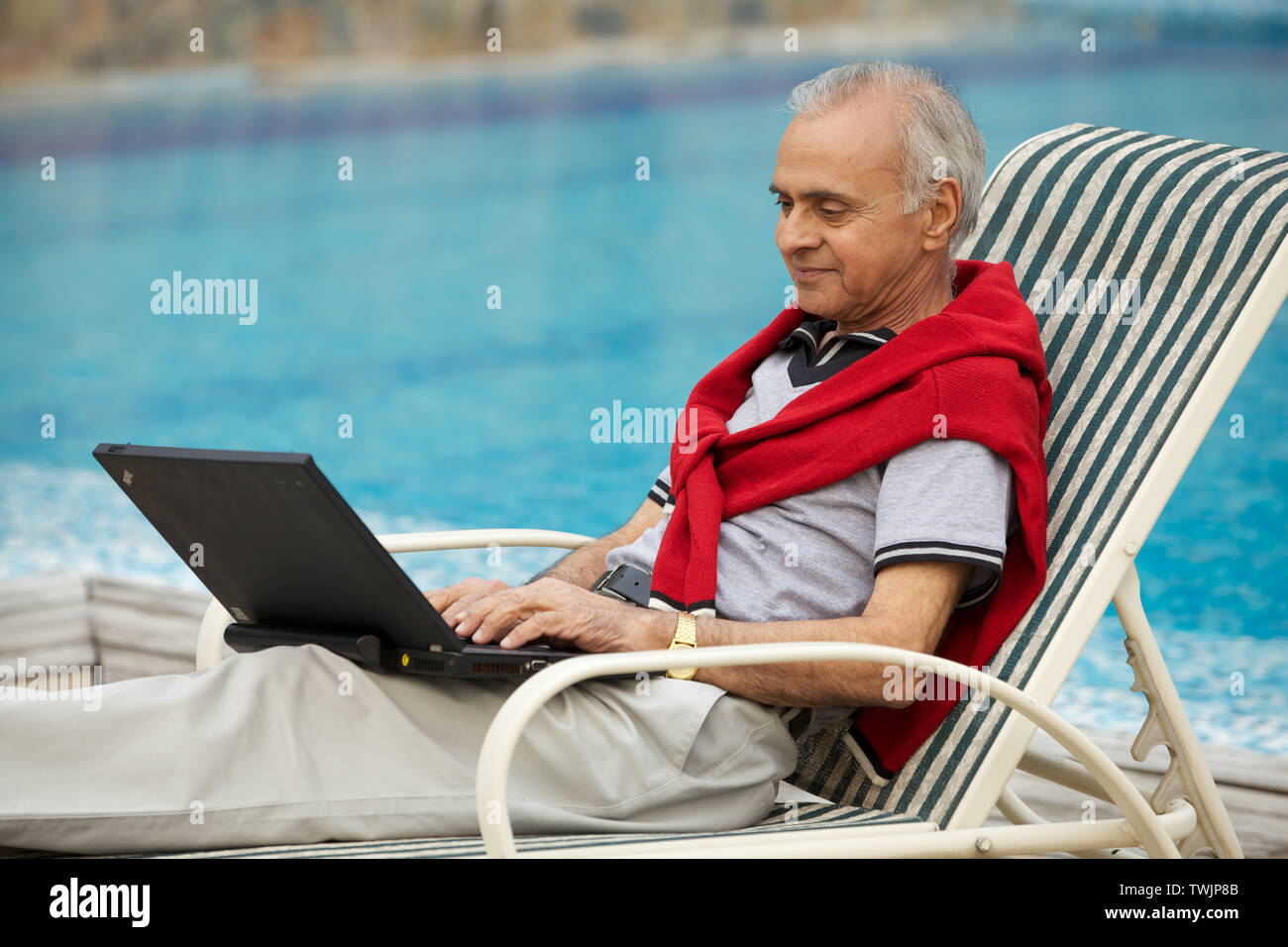 Old man using a laptop by the pool Stock Photo - Alamy