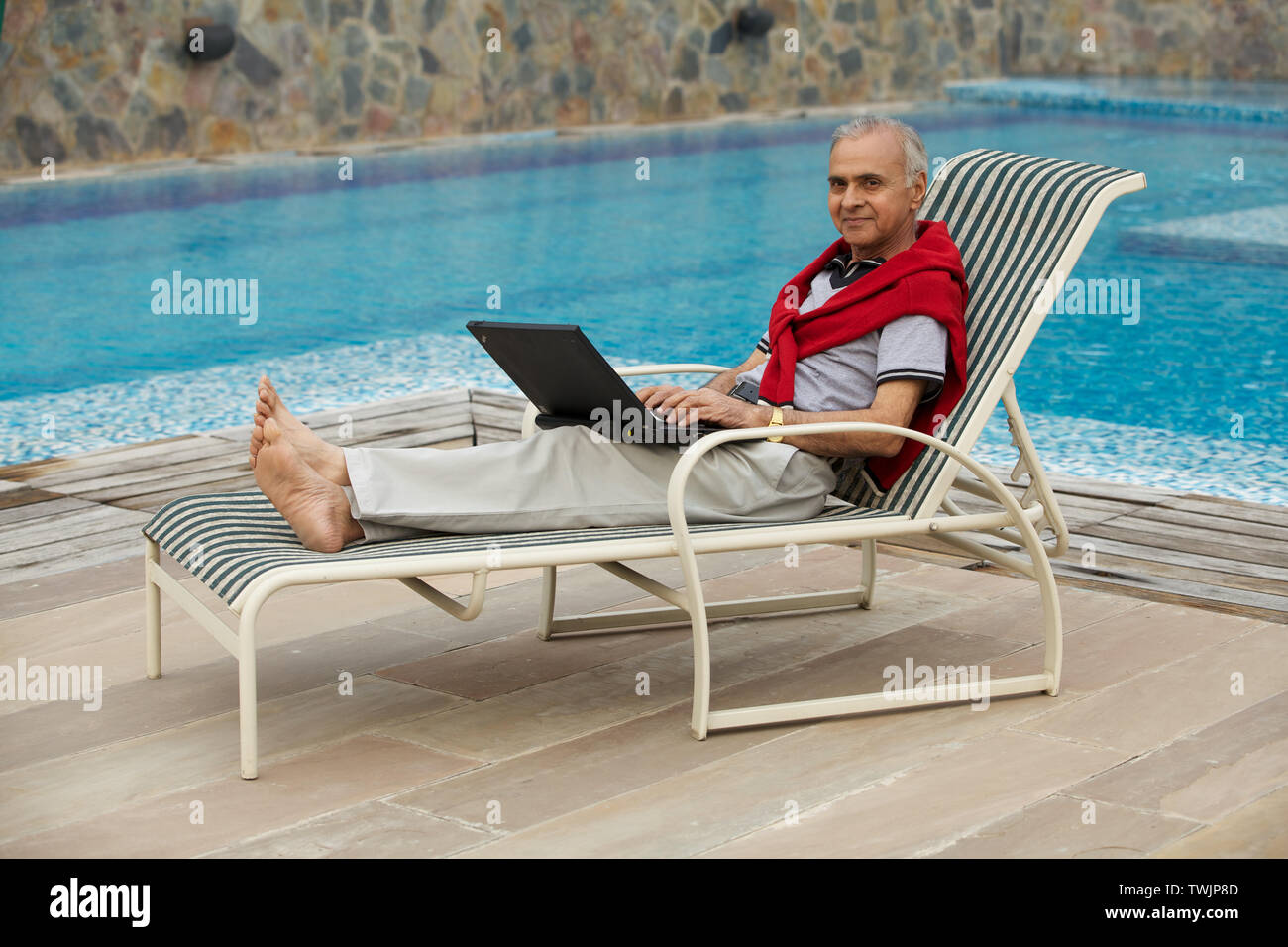 Old man using a laptop by the pool Stock Photo - Alamy